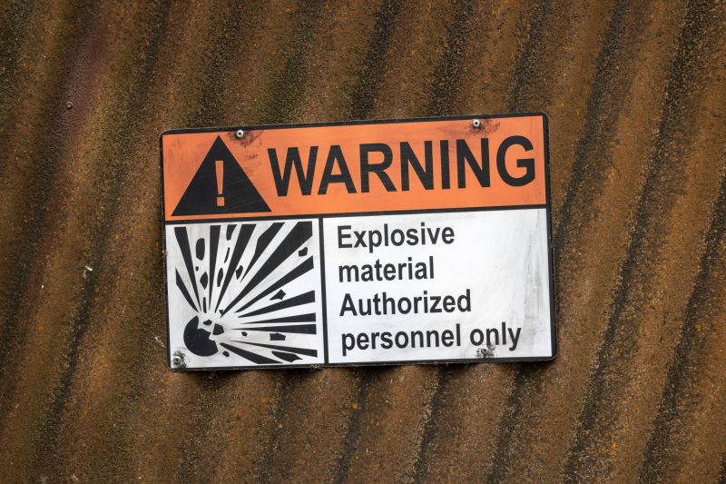 Warning sign on a corrugated iron wall with the inscription: explosive ...